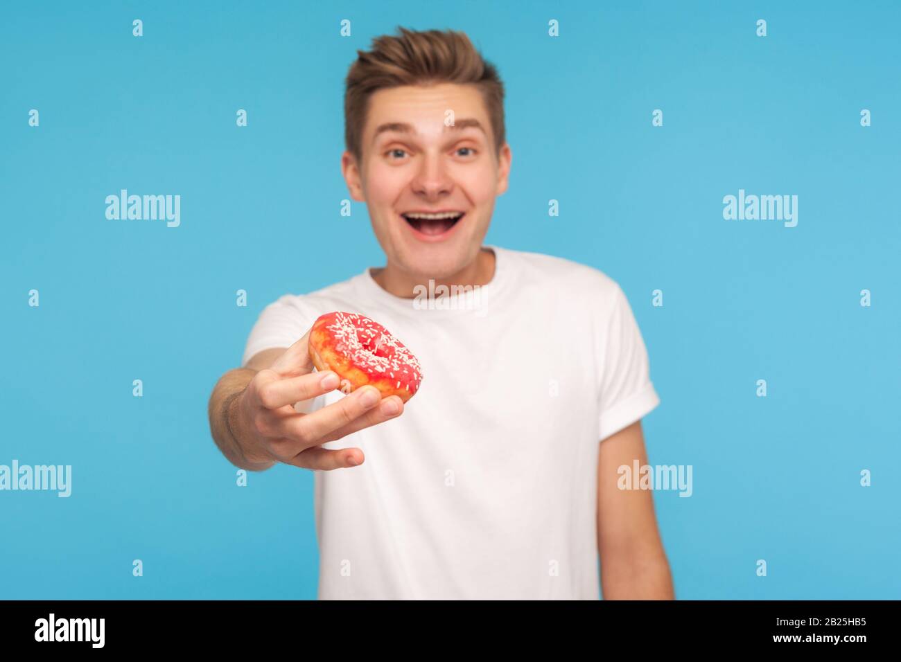 Take donut for snack! Happy delighted man giving pink doughnut to ...