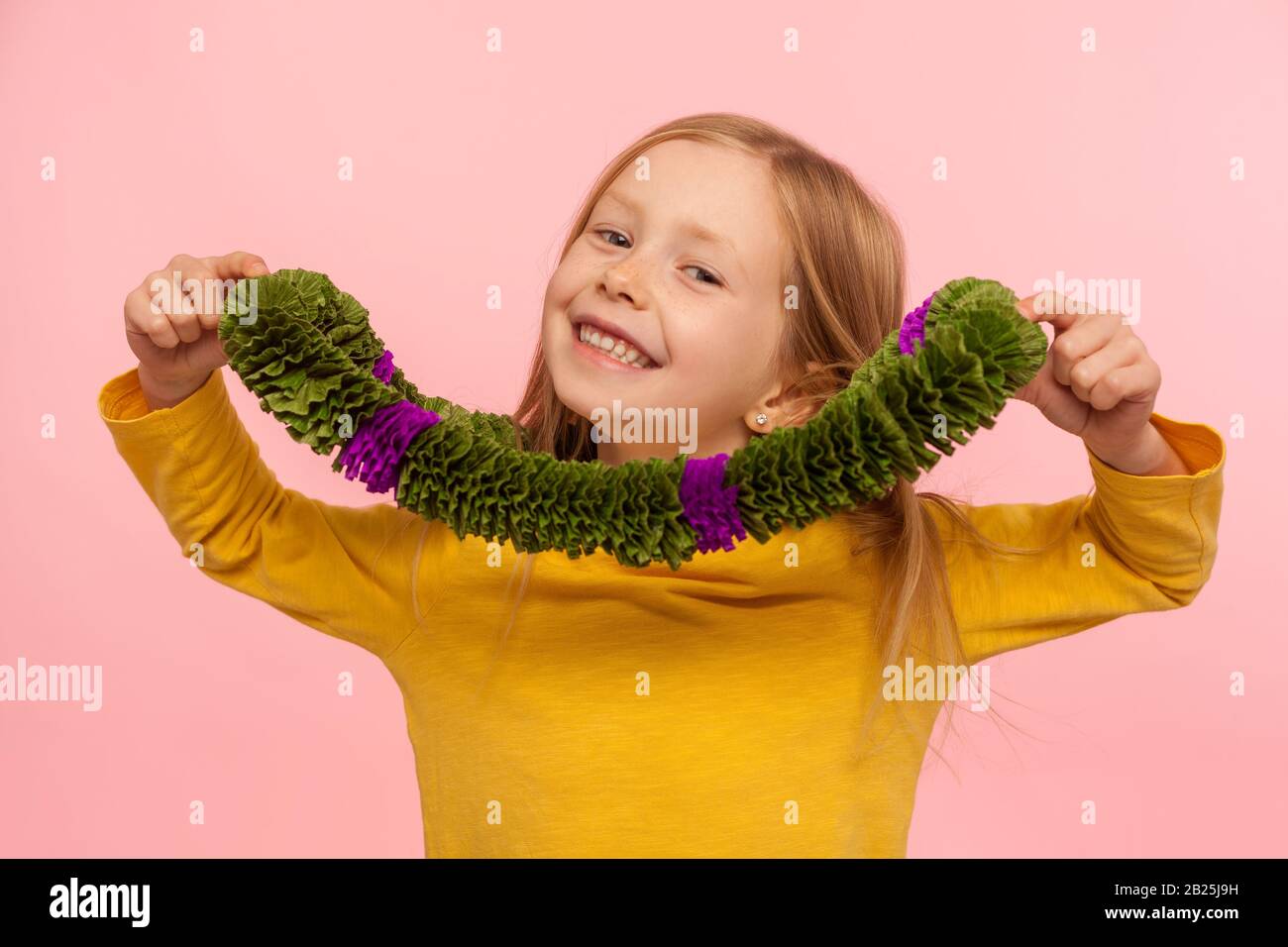 Portrait of happy preschool child wearing green wreath around neck and ...