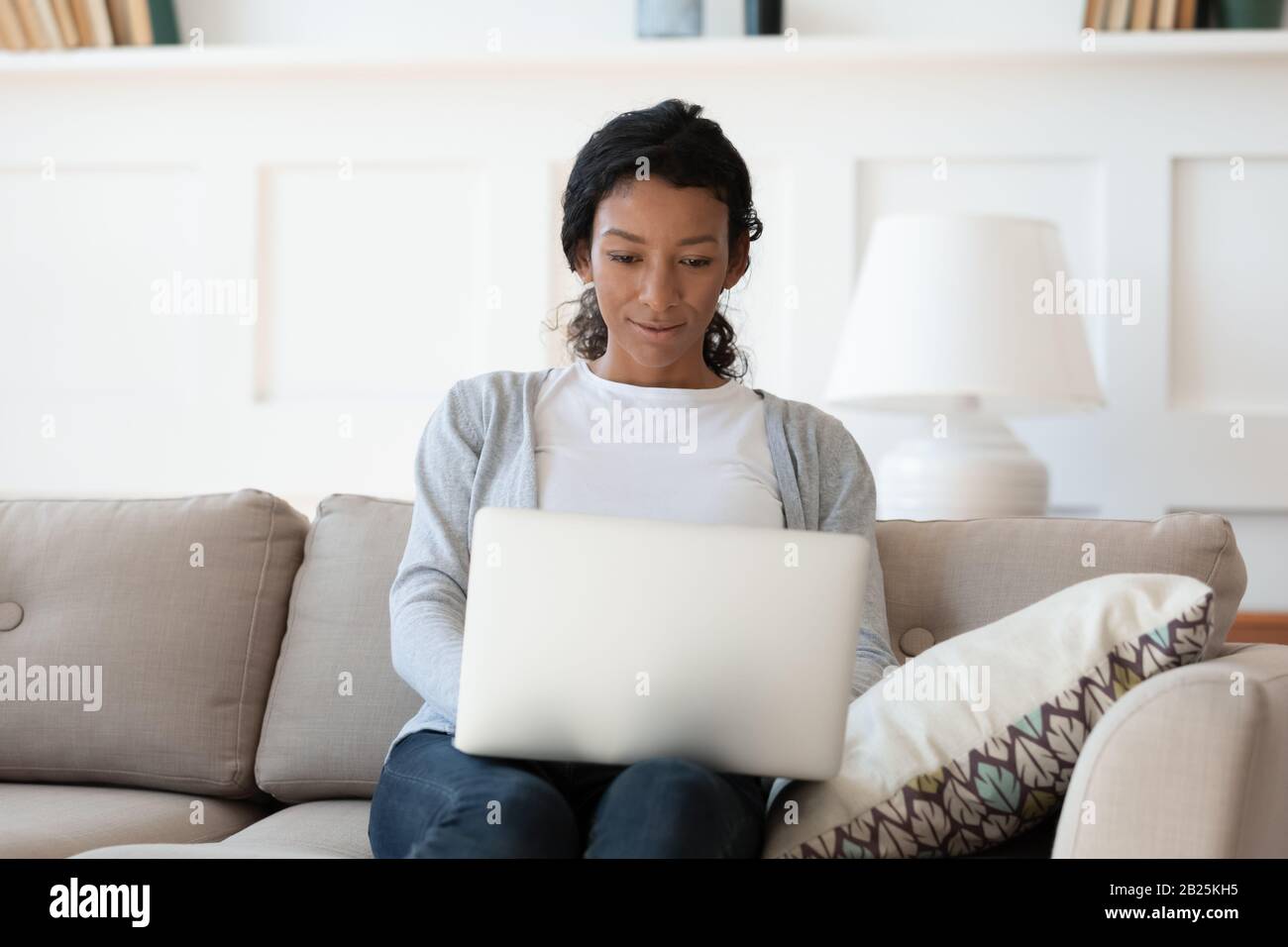 Young biracial woman rest on couch using laptop Stock Photo - Alamy