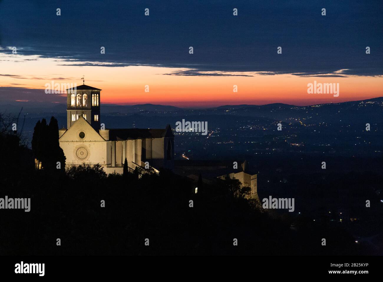 View of St. Francis papal church in Assisi at night, with city lights ...