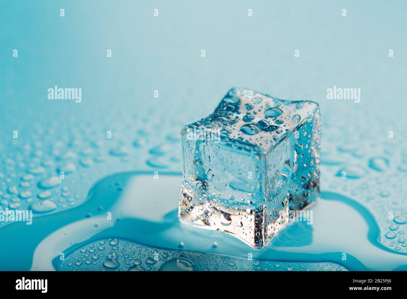 Ice cube with water drops on a blue background. The ice is melting ...