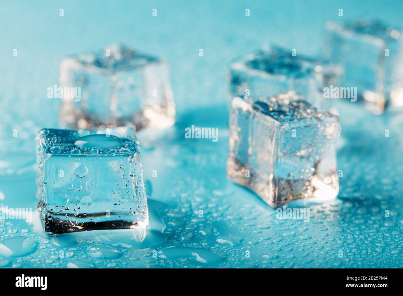 Ice cubes are scattered with water drops scattered on a blue background ...