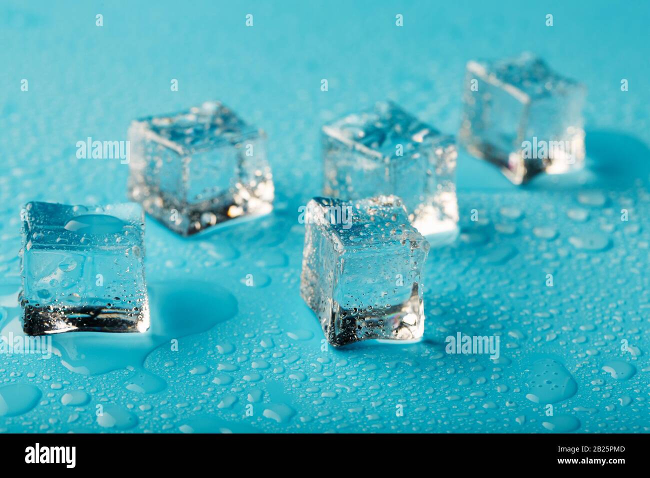 Ice cubes are scattered with water drops scattered on a blue background ...