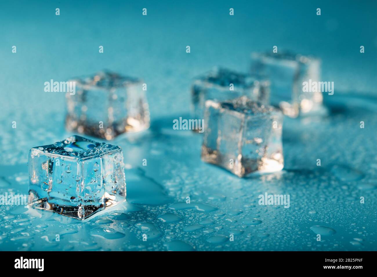 Ice cubes are scattered with water drops scattered on a blue background ...