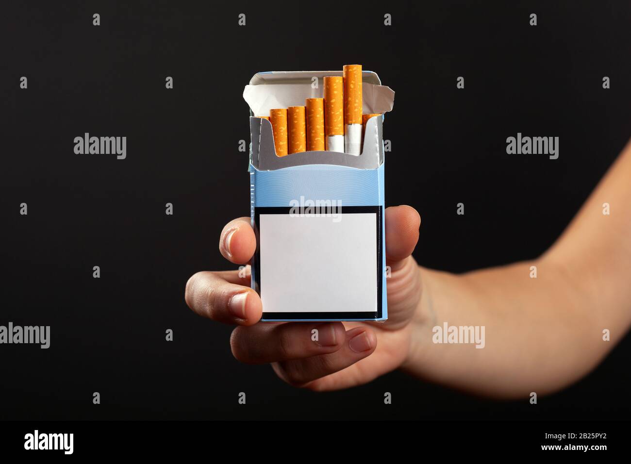 blue pack of cigarettes in hand on a dark background, mockup Stock ...