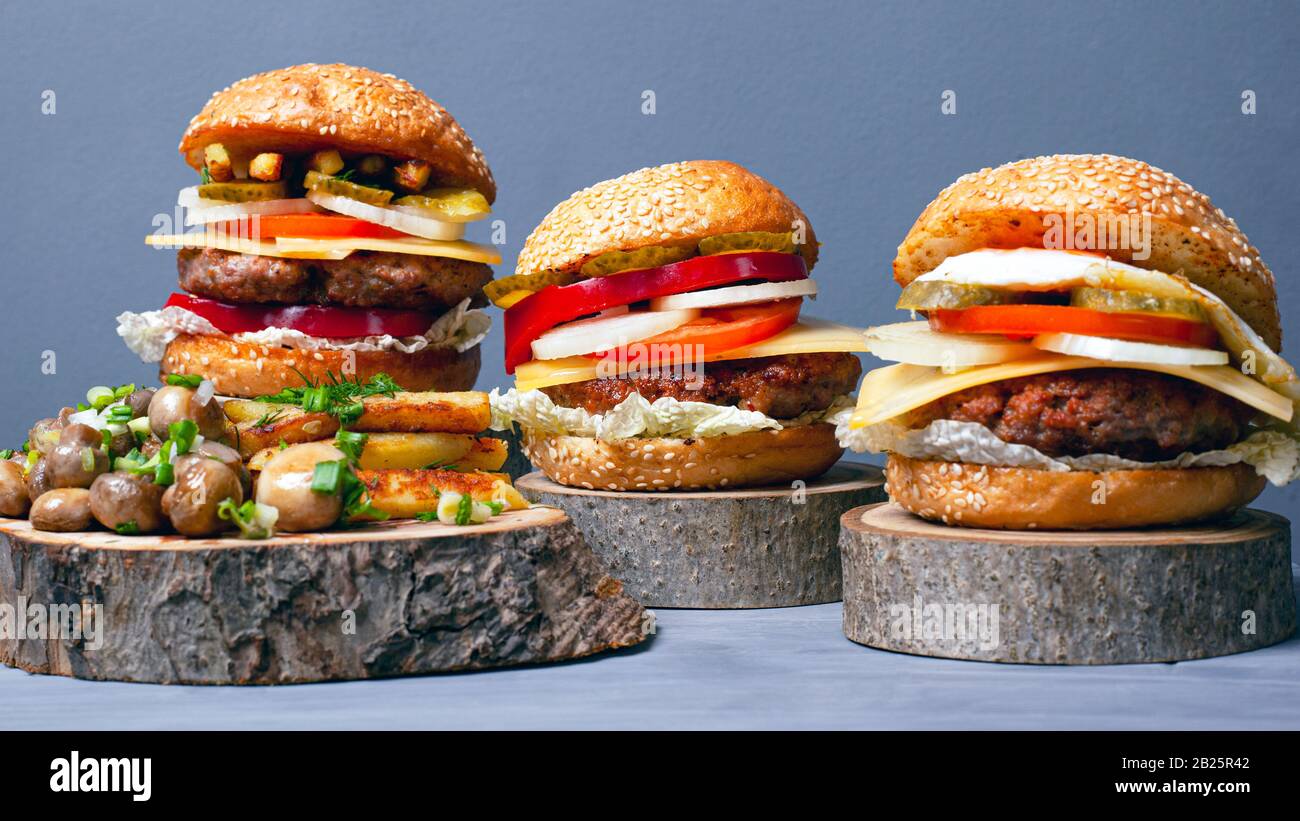 fried potatoes with mushrooms and juicy meat burgers on wooden stumps ...