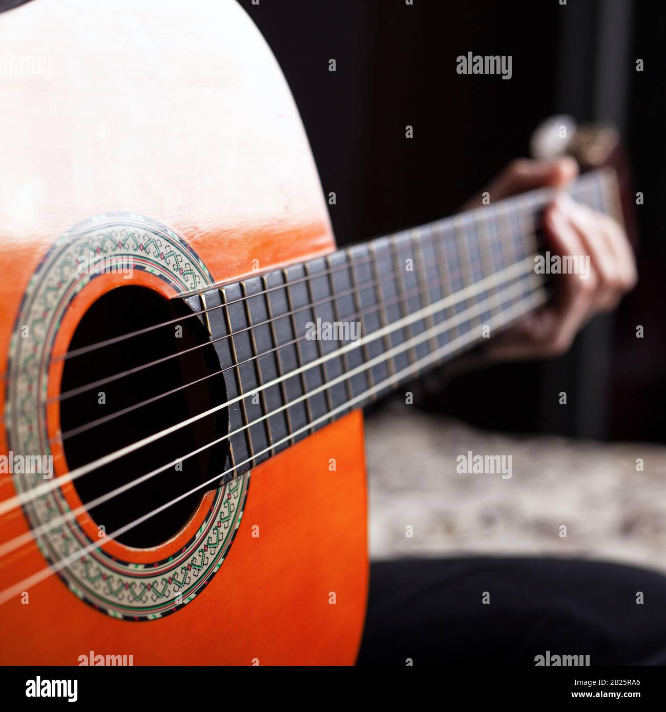 hand on fretboard acoustic guitar orange color Stock Photo - Alamy