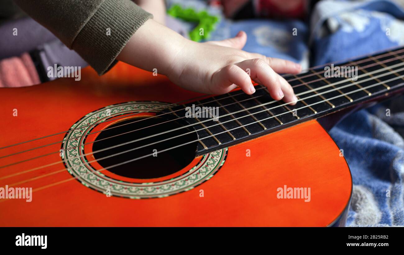 children's hand touches the strings on an acoustic six-string guitar ...