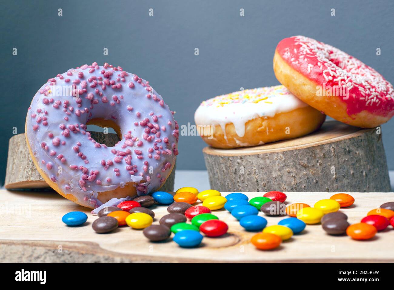 sweet colored donuts with icing and assorted candy on forest decorative ...