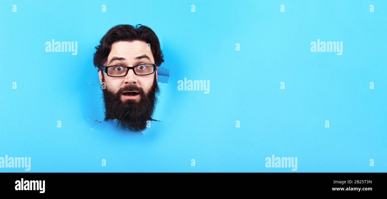 surprised bearded man in hole in the blue background, panoramic mock-up ...