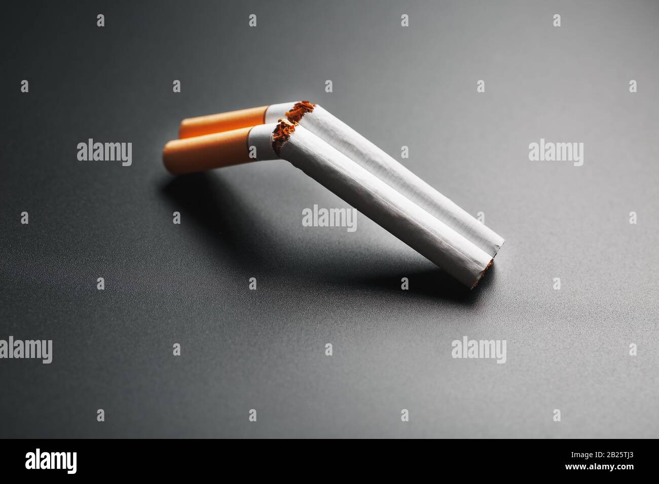 Two cigarettes in the form of a double-barreled shotgun on a black ...