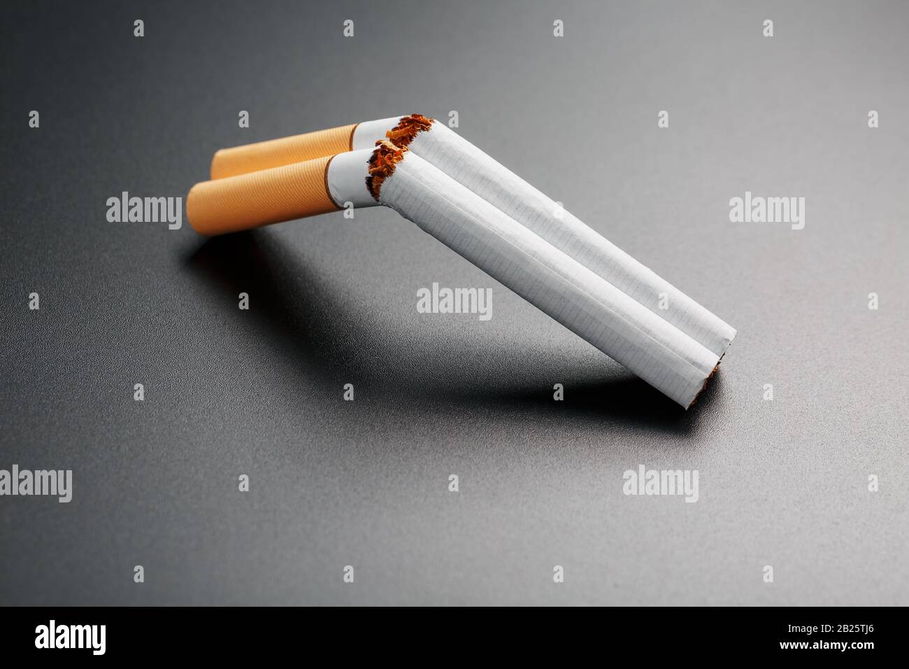Two cigarettes in the form of a double-barreled shotgun on a black ...
