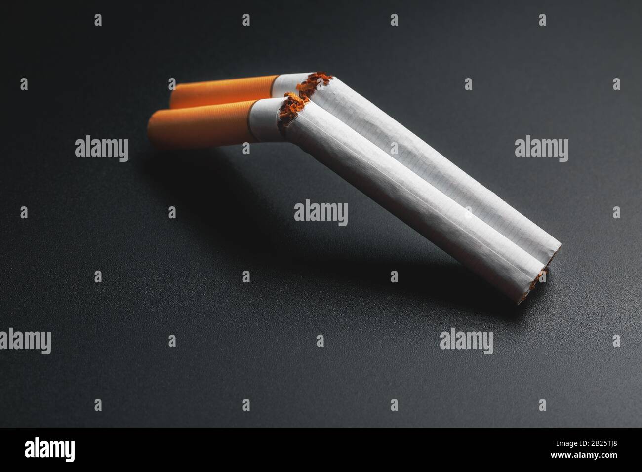 Two cigarettes in the form of a double-barreled shotgun on a black ...