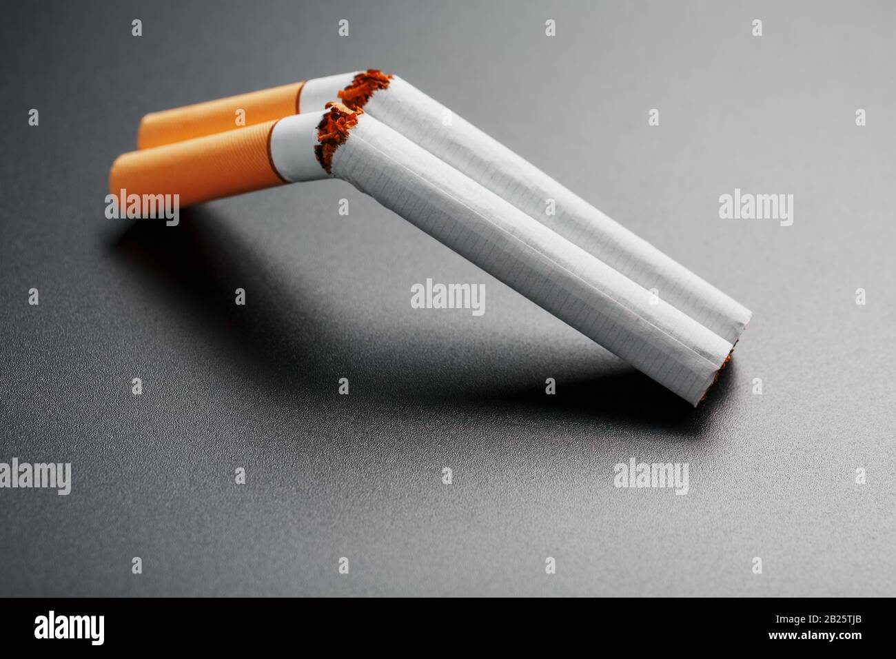 Two cigarettes in the form of a double-barreled shotgun on a black ...