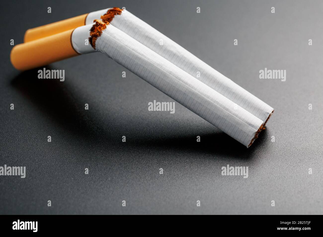 Two cigarettes in the form of a double-barreled shotgun on a black ...