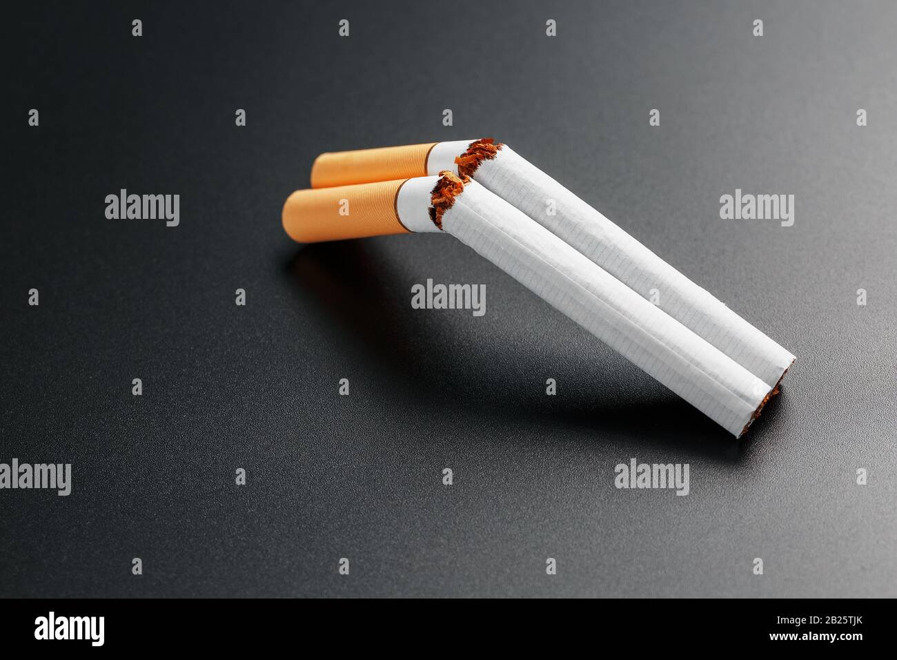 Two cigarettes in the form of a double-barreled shotgun on a black ...