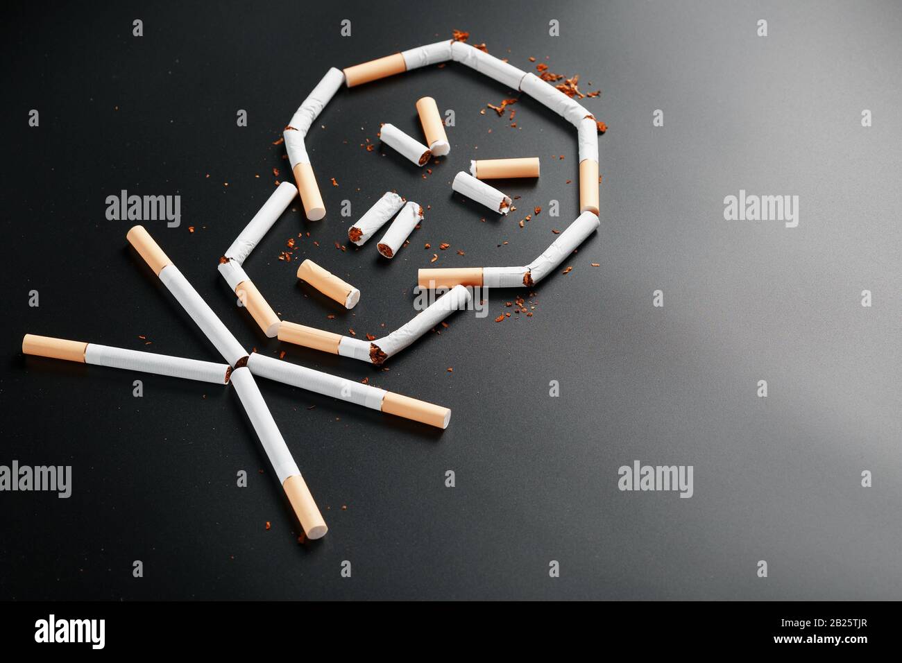 Skull from cigarettes on a black background. The concept of smoking ...