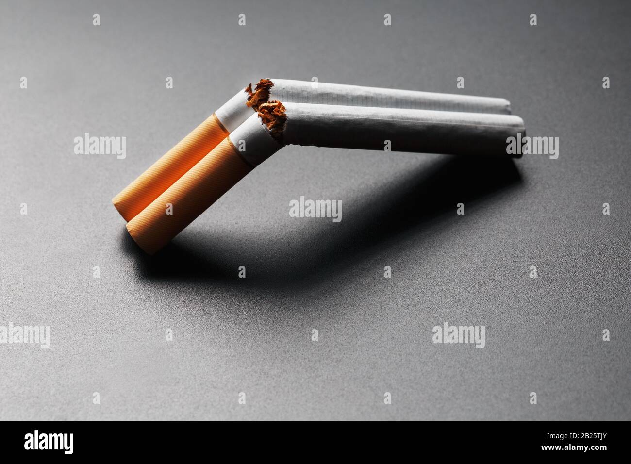 Two cigarettes in the form of a double-barreled shotgun on a black ...