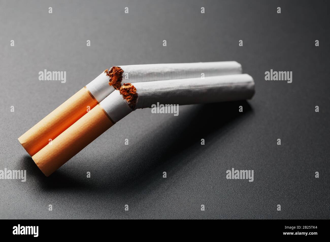 Two cigarettes in the form of a double-barreled shotgun on a black ...