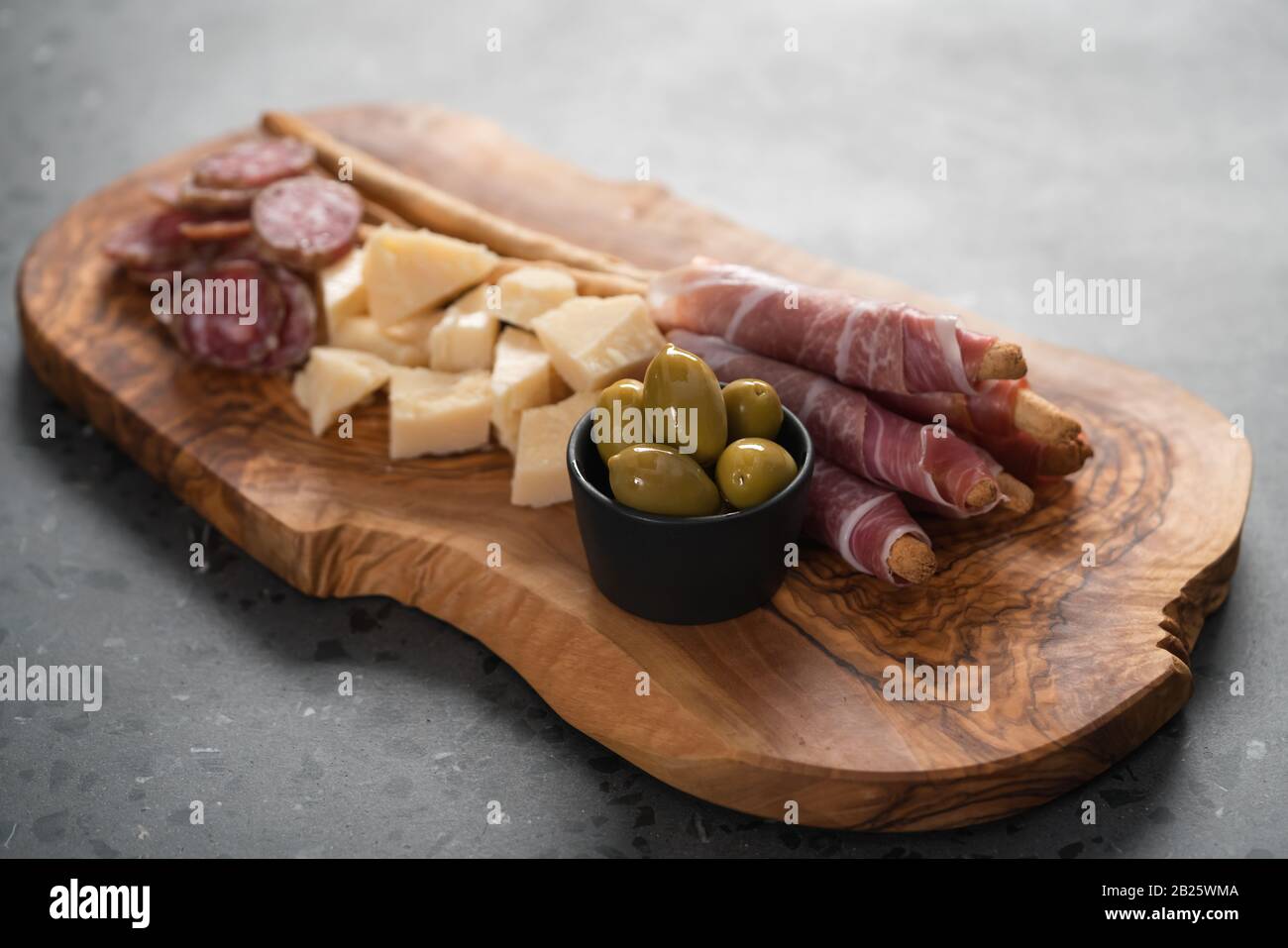 Italian snacks on olive wood board, shallow focus Stock Photo - Alamy