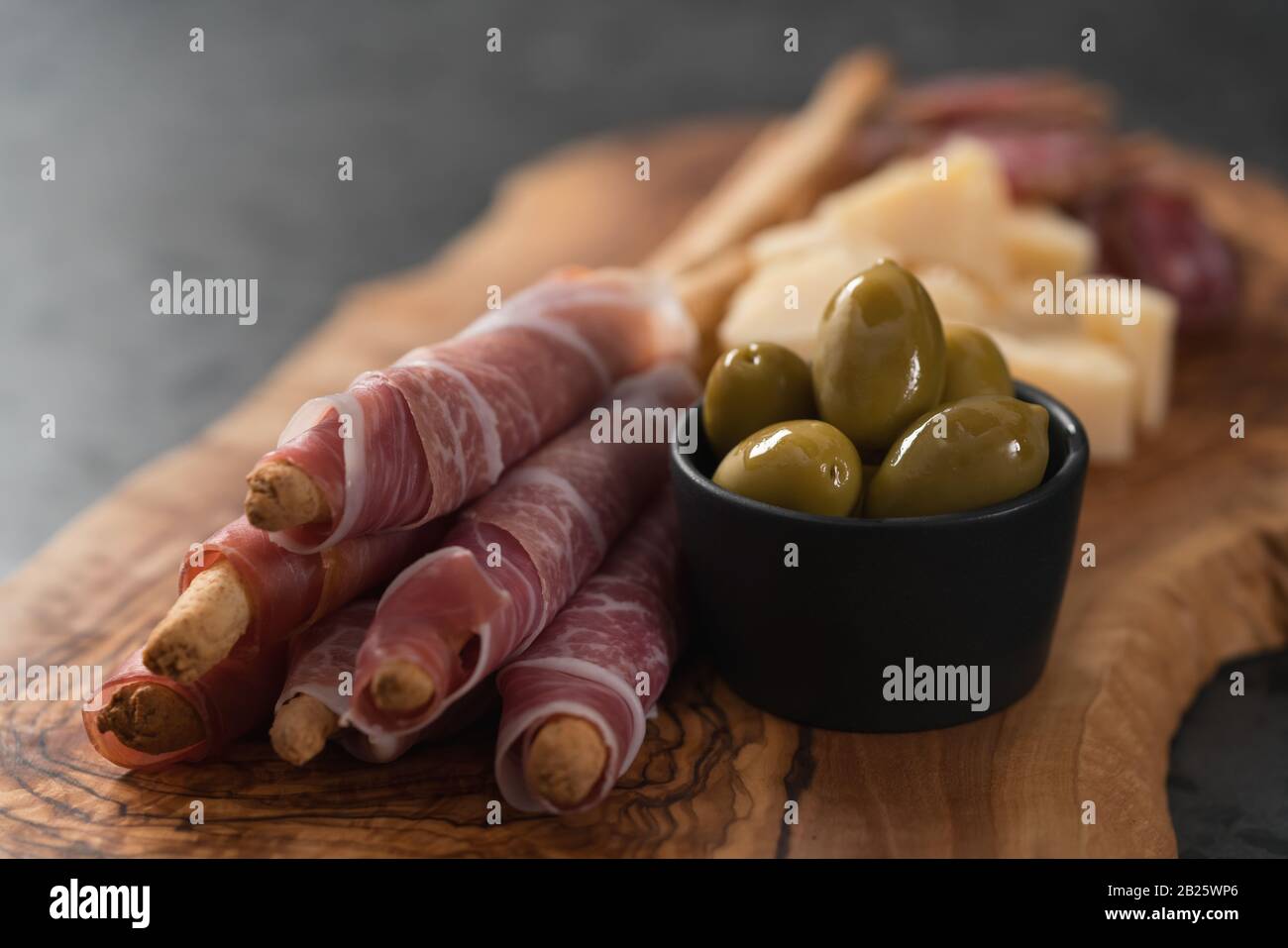 Italian snacks on olive wood board, shallow focus Stock Photo - Alamy