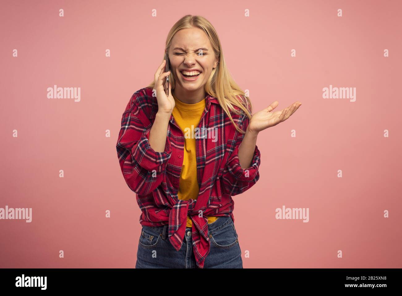 Very happy girl talk with a friend on the mobile phone. Pink studio ...