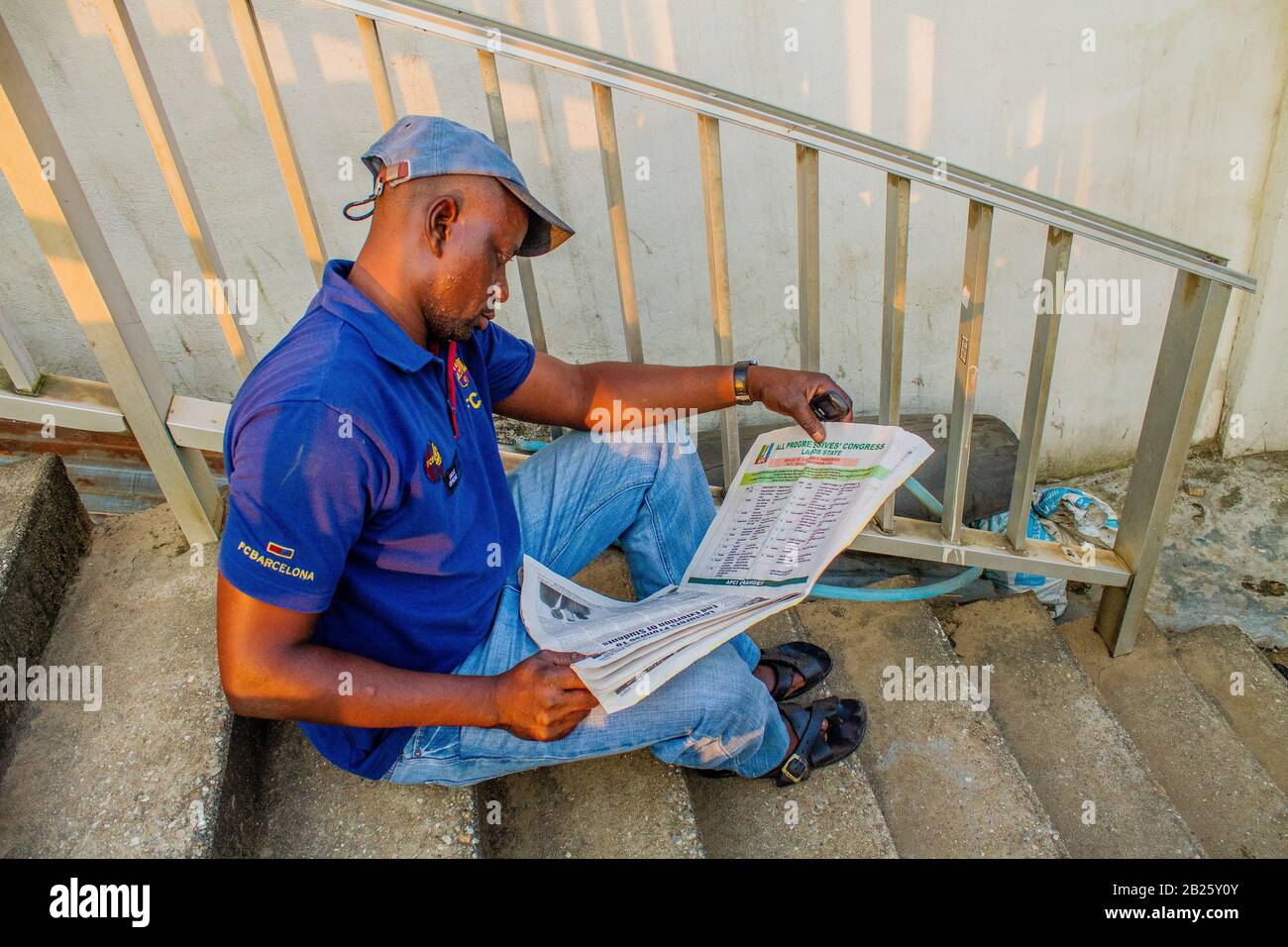 A man reads newspaper on a street in Lagos, Nigeria Stock Photo - Alamy
