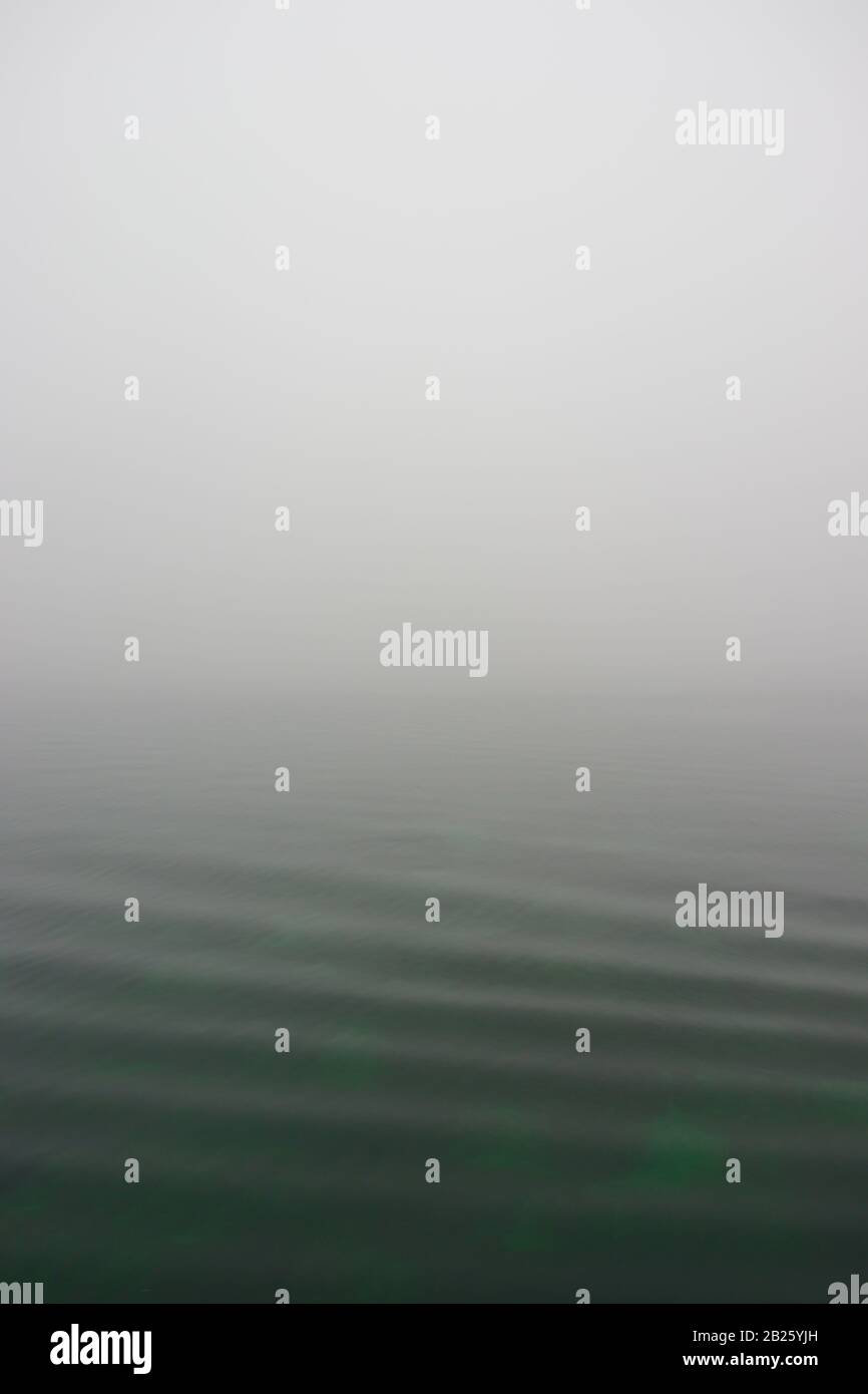 Waves rippling through water fading off into fog showing concept of ...