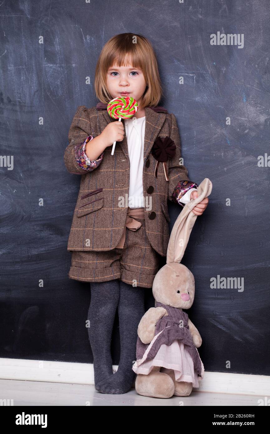 Beautiful cute little girl with toy eating lollipop Stock Photo - Alamy