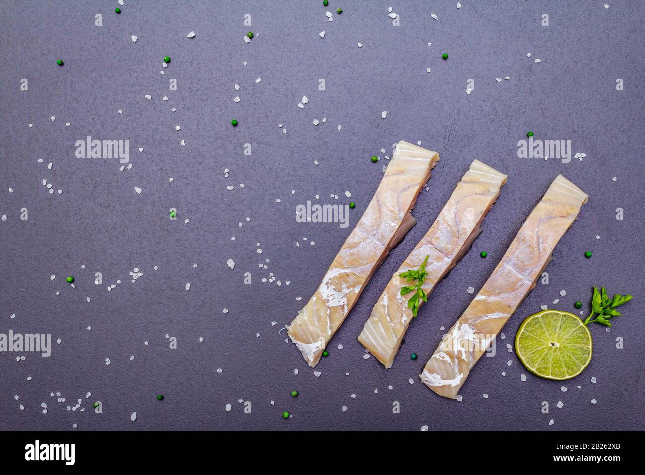 Fresh pollock pieces with lime, green pepper, salt and parsley. Concept ...