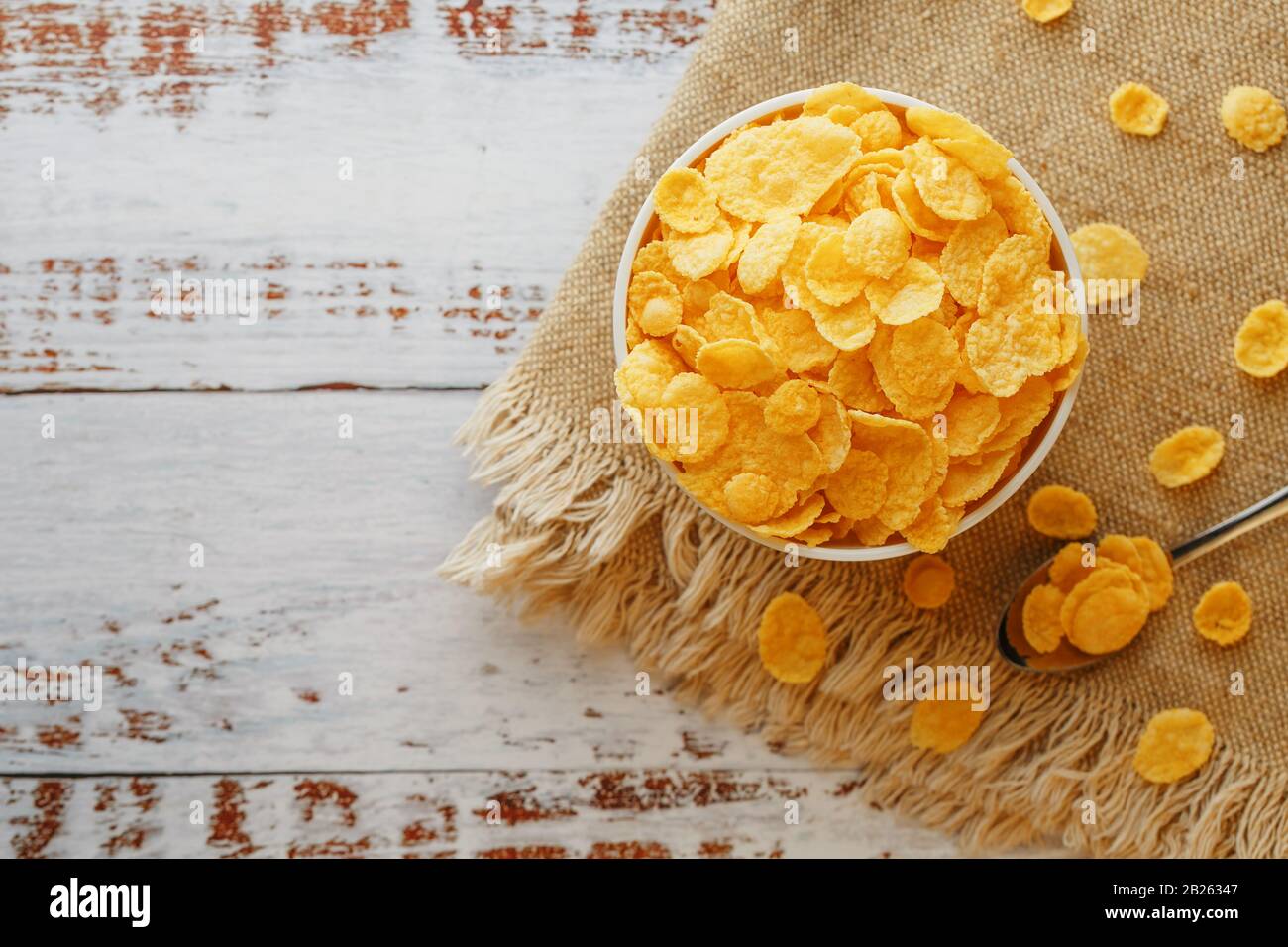 Bowl with golden flakes on a linen, on a light wooden table, next to a ...