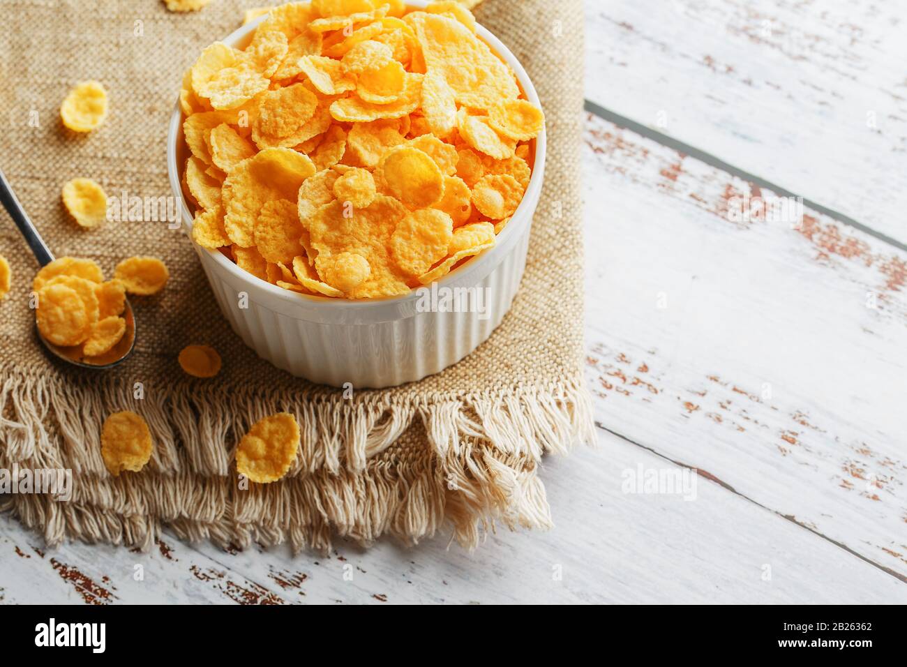 Bowl with golden flakes on a linen, on a light wooden table, next to a ...