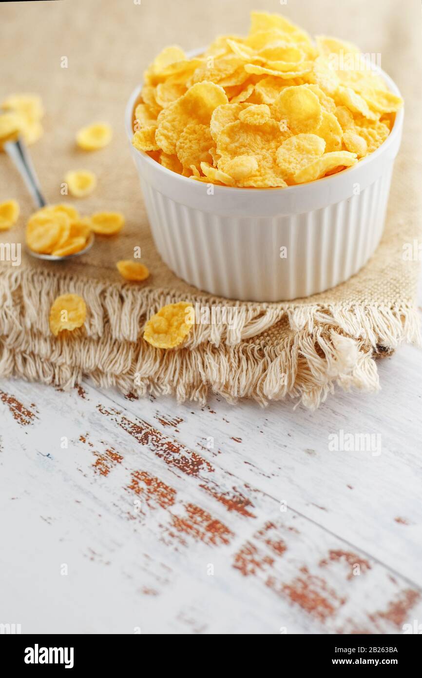 Bowl with golden flakes on a linen, on a light wooden table, next to a ...