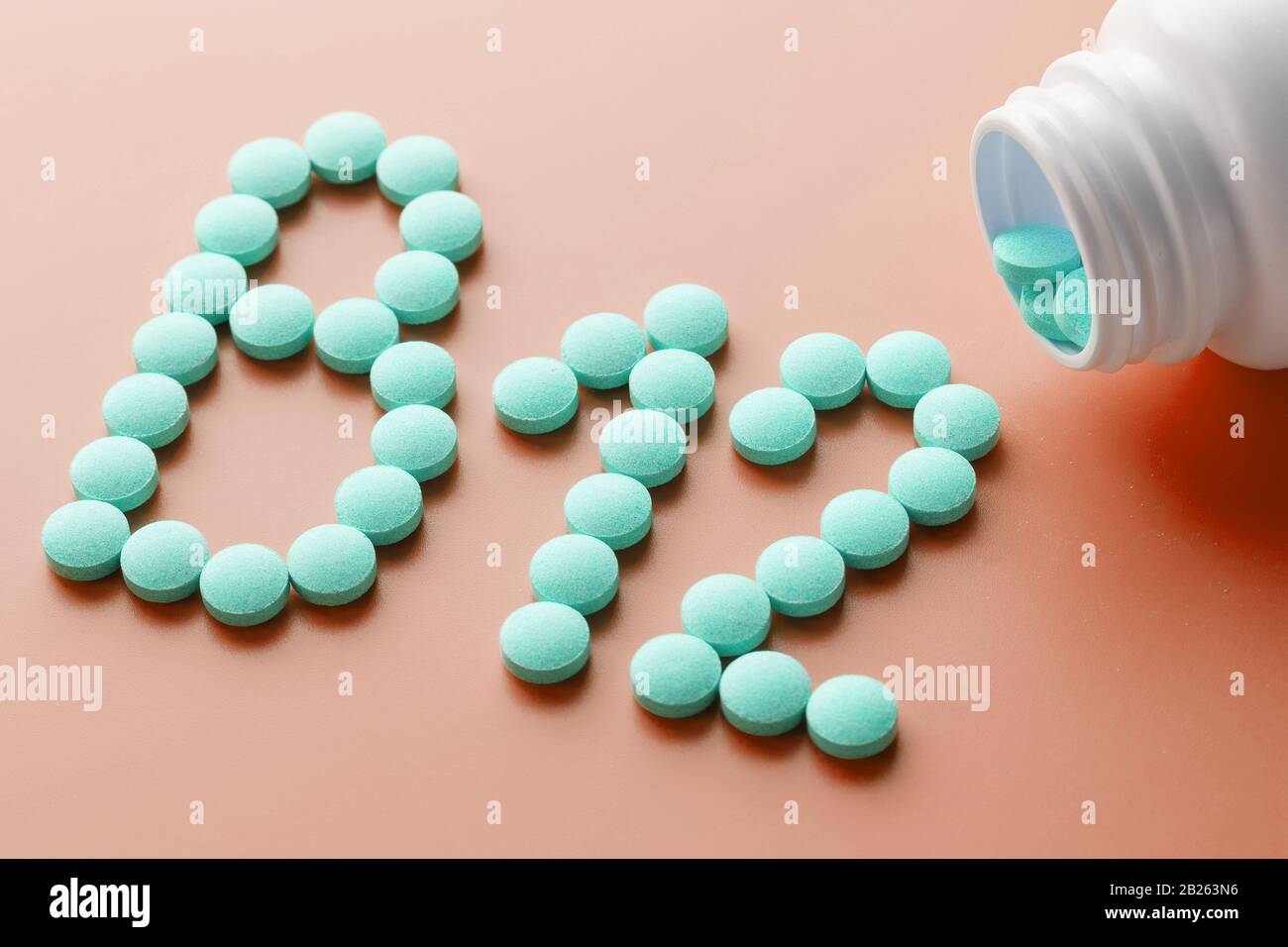 Vitamins B 12 on a red substrate, poured out of a white jar. The ...
