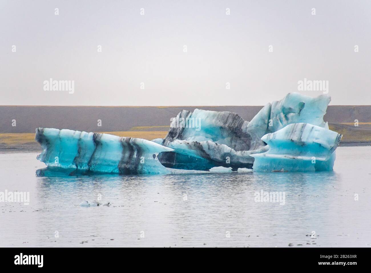 Joekulsarlon Glacier Lagoon deep blue iceberg with dark layers of ...