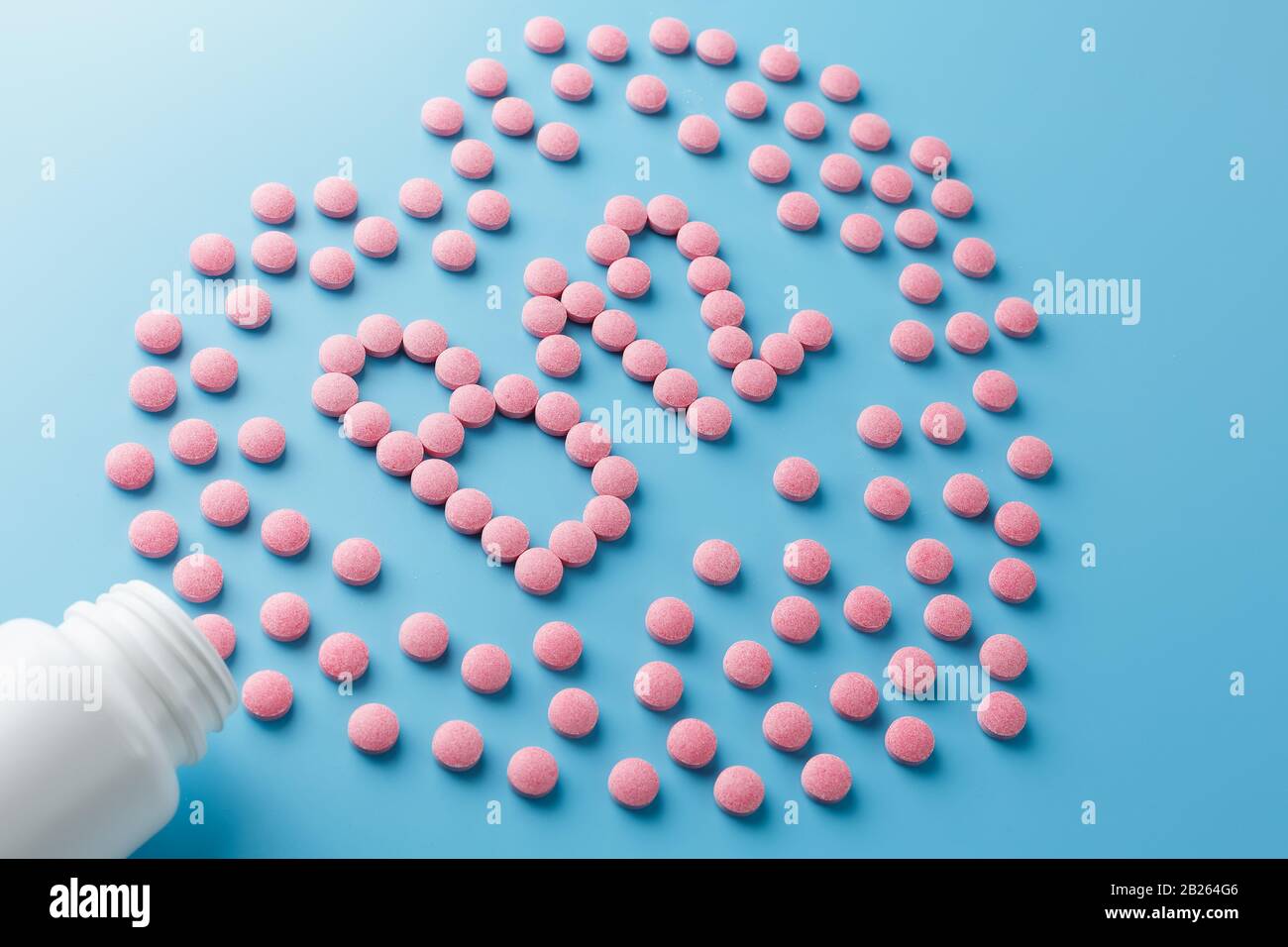 Pink tablets in the form of B12 in the heart on a blue background ...