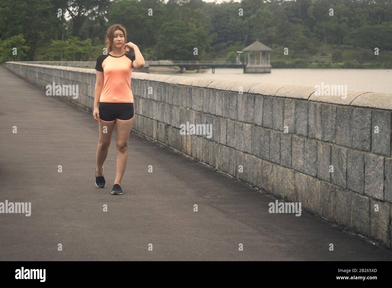 Asian Chinese girl in her sports outfit walking in nature park after ...