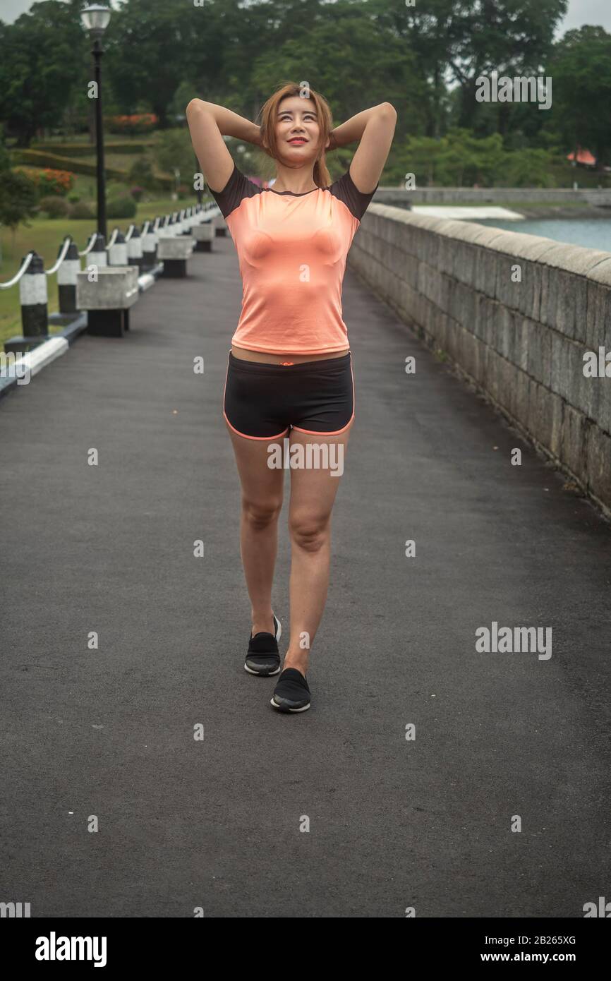 Asian Chinese girl in her sports outfit walking in nature park after ...