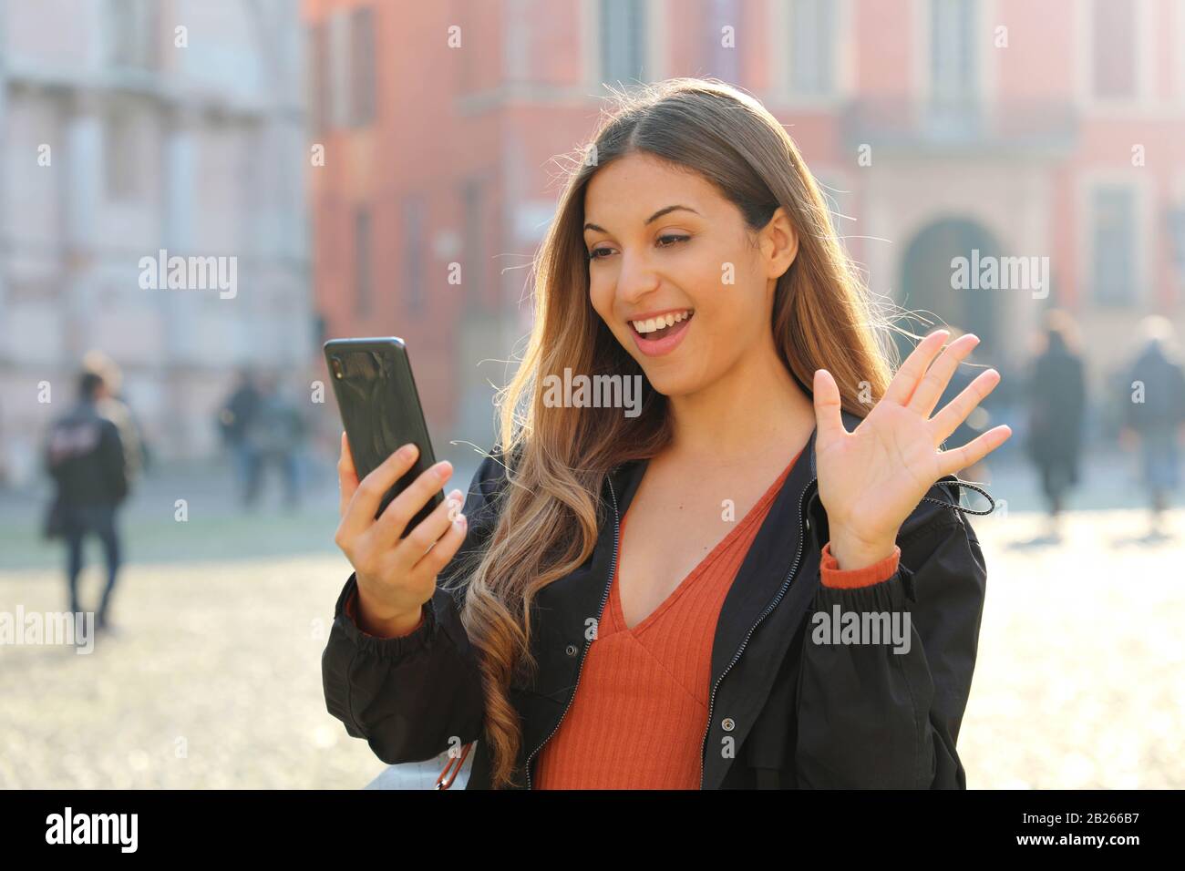 Happy lady greeting during a video call with a smart phone on city ...