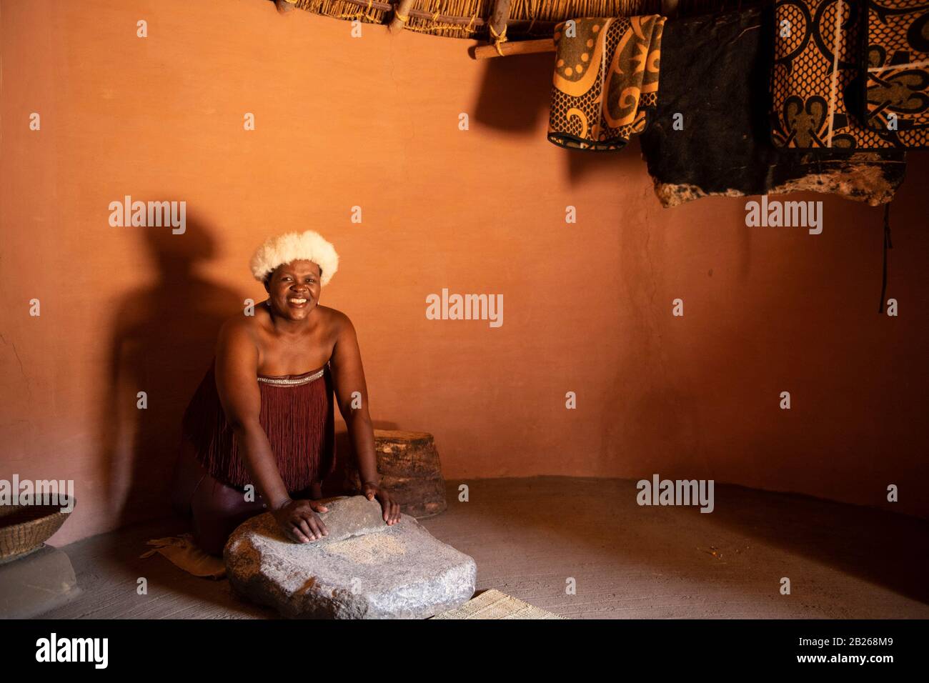Basotho woman grinding maize in a traditional hut, Thaba Bosiu Cultural ...