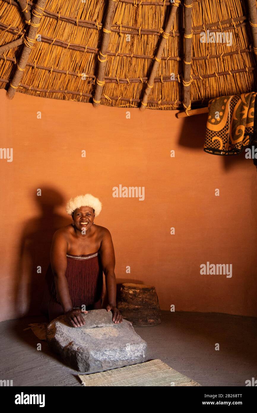 Basotho woman grinding maize in a traditional hut, Thaba Bosiu Cultural ...