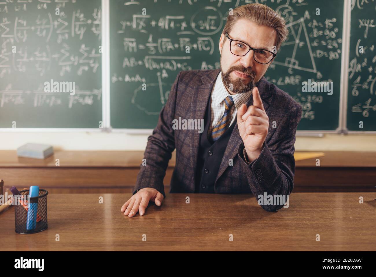 College math teacher with beard and glasses holding a trigonometry ...