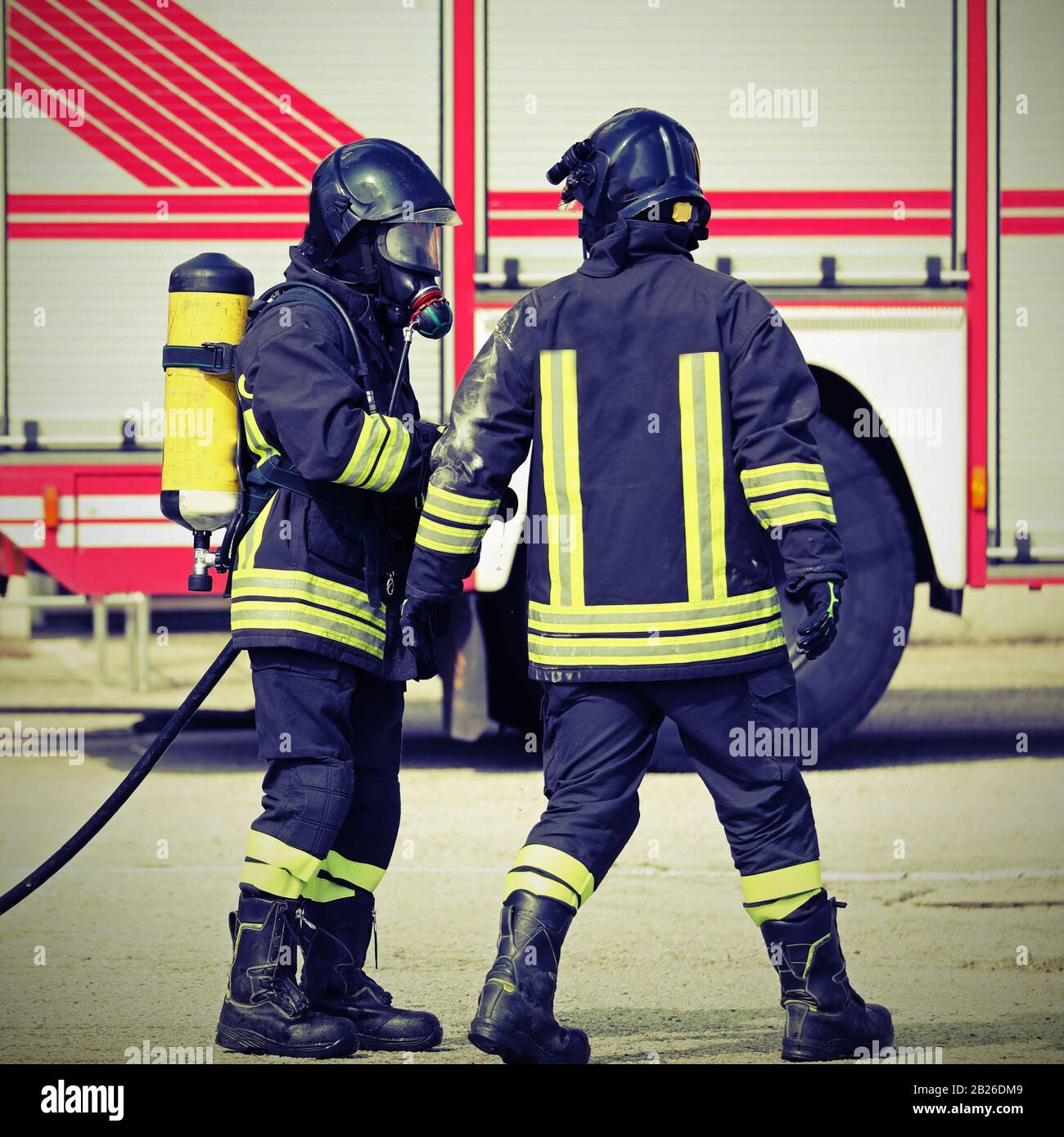 two firemen with uniform and breathing apparatus during an emergency ...