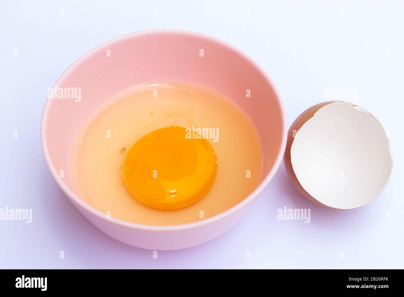 Egg yolk in a pink bowl with an eggshell on the white background Stock ...