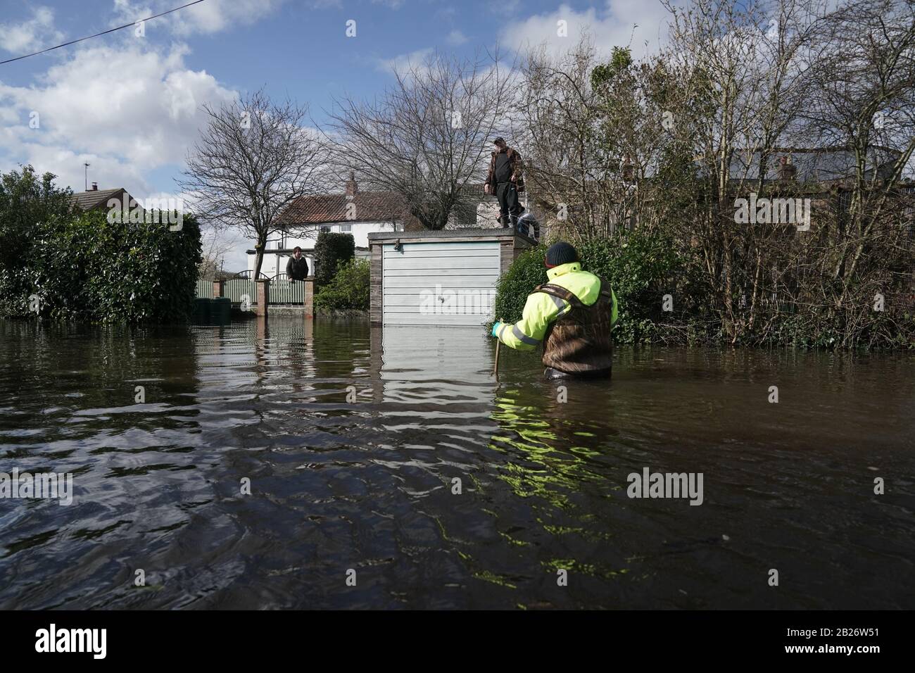 Rescue workers wade through water in the flooded village of East Cowick ...