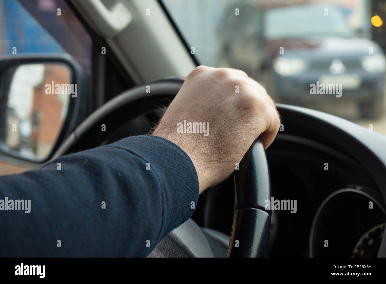 Man's hand holding the steering wheel of a car close-up taxi driver ...