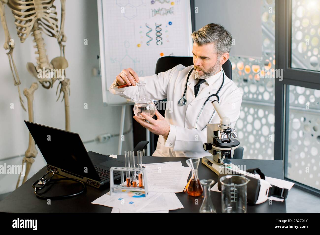 Mature Caucasian male doctor researcher carrying out scientific ...