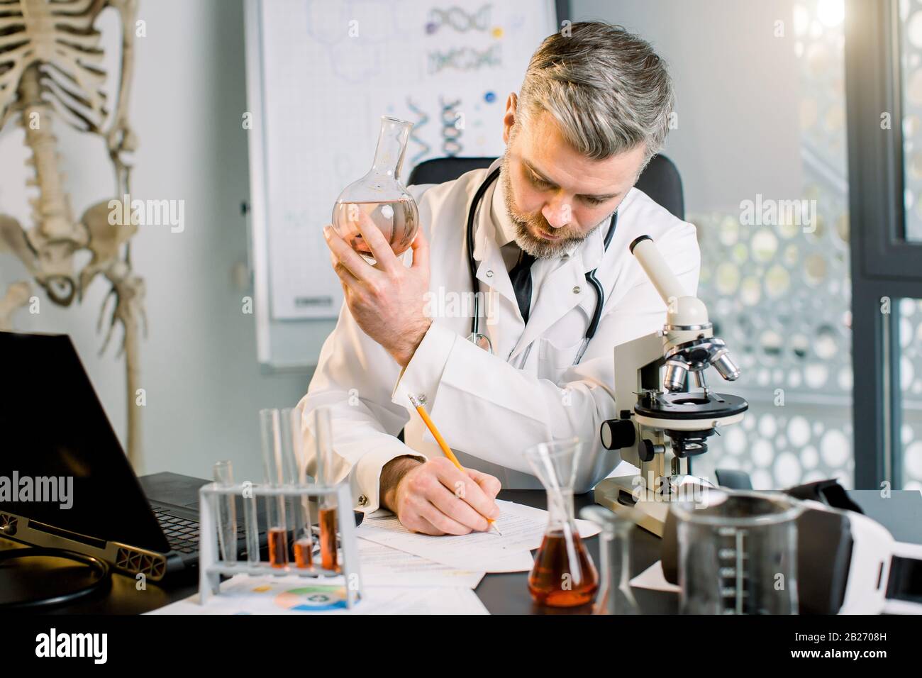 Male senior scientist chemist, conducts experiments by synthesising new ...