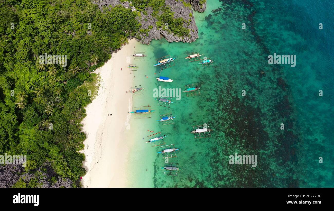 Tropical beach with tourists surrounded by blue water, aerial view ...
