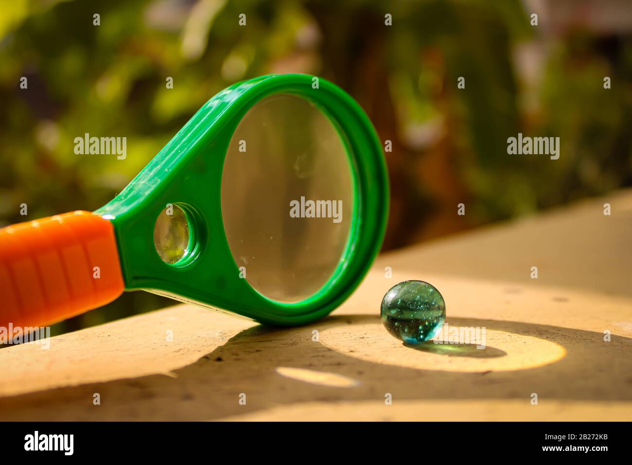 Magnifier on the sunlight with green three marbles on light passing in ...
